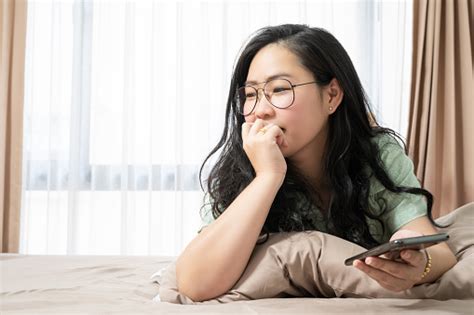 아름다운 안경 아시아 여성은 그녀의 뱃속에 누워 파스텔 녹색과 그녀의 침실에서 침대에서 모바일을 재생 갈색 색상 테마 30 34세에 대한 스톡 사진 및 기타 이미지 Istock