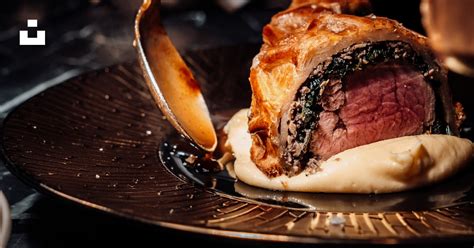 스테인레스 스틸 포크와 칼을 들고 검은 세라믹 접시에 고기를 자르는 사람 사진 Unsplash의 무료 방콕 이미지