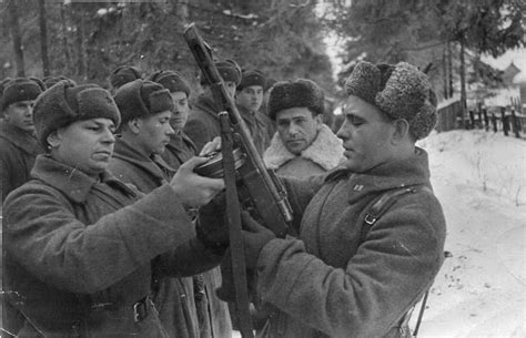 Батальонный комиссар Г Поляков осматривает оружие у разведчиков — военное фото