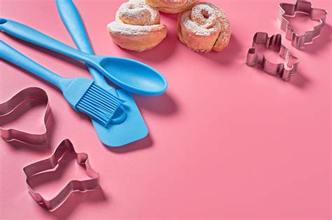 금속 스텐실과 고무 주걱 브러시 숟가락 은 분홍색 책상에 놓여 있는 금속 스텐실과 고무 주걱 근처 가루 설탕의 장미 의 형태로 많은 수제 구운 빵의 힙 제과 작업장 텍스트를