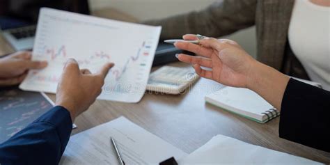 Teamwork In Tax Analysis Professionals Collaborating On Financial Graphs And Reports At A Desk