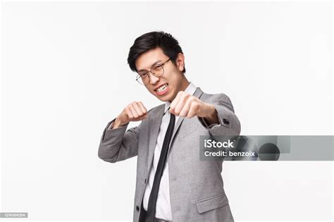 결정 자기 확신 잘 생긴 아시아 사업가의 허리 업 초상화 제기 꽉 주먹과 심각한 찡그린 얼굴 펀치 공기와 권투 포즈에 서 거울