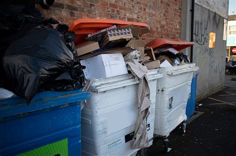 영국 글로스터셔 주 첼튼햄에 있는 상점 뒤쪽에서 버려진 골판지 검은 색 쓰레기통 라이너 및 종이로 가득 찬 쓰레기 쓰레기 쓰레기 쓰레기 바퀴통 0명에 대한 스톡 사진 및