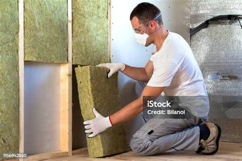 보호 고글및 호흡보호구에서 작업자가 차가운 장벽을 위한 미래의 집 벽을 위해 나무 프레임에 바위 울 절연을 절연합니다 편안한 따뜻한 집 경제 건설 및 리노베이션 개념