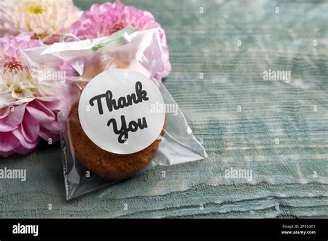 bag of cookies with phrase thank you and flowers on grey wooden table
