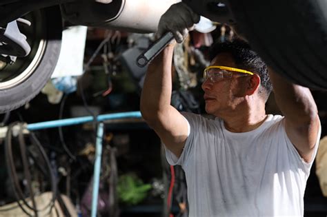 남자 기술자 자동차 정비사는 반쯤 제복을 입고 정비를 점검하고 수리 차고 역에서 리프트 자동차 서비스를 제공합니다 렌치를 들고