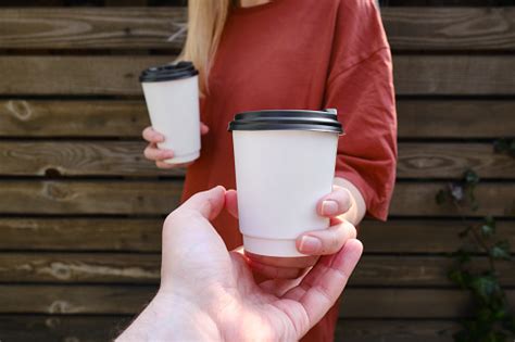 여자와 남자의 손에 커피가 든 하얀 종이 컵 도시에서 커피를 마실 시간 갈 커피 순간을 즐기고 휴식을 취하십시오 일회용 종이컵 클로즈업 맛있는 뜨거운 음료 모형 종이