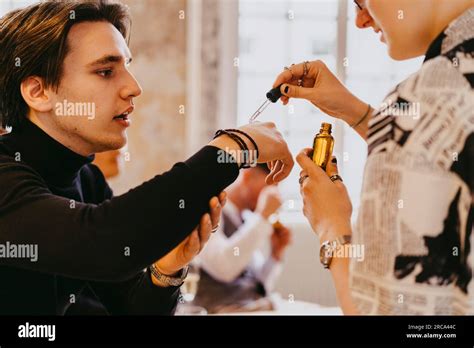 Non Binary Person Testing Essential Oil Sample On Male Colleagues Hand