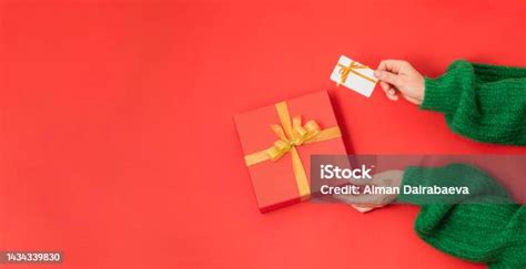 플랫 레이 황금 새틴 리본 활과 흰색 플라스틱 카드가있는 빨간 선물 상자를 복사 공간이있는 고립 된 빨간색 배경에 들고 있는 손 생활필수품에 대한 스톡 사진 및 기타 이미지
