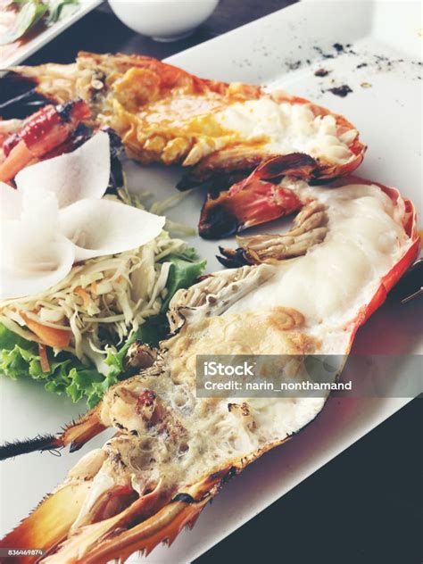 맛 있는 구운 거 대 한 강 새우 고추와 센터 레스토랑 나무 테이블에 작은 그릇에 간장 소스와 함께 흰색 접시에 파 슬 리의 위에서 볼 태국 스타일 음식입니다 빈티지 톤