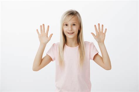 Удивленная милая девушка поднимает руки вверх и улыбается Бесплатно Фото