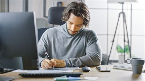 잘생긴 긴 머리 기업가 는 사무실의 책상에 앉아 데스크톱 컴퓨터에서 작동 문서와 작업 차트 그래프 통계 및 회사 전략 서류를 채우는 사업가 25 29세에 대한 스톡 사진 및