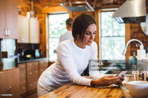 Woman Leaning Against The Kitchen Counter Scrolling Through Social