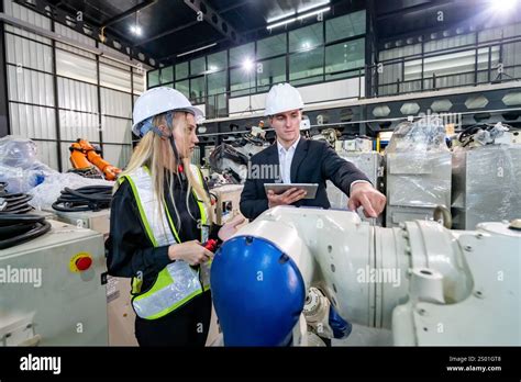 Two Engineers Discuss A Robotics Project While Inspecting Machinery In A High Tech Manufacturing