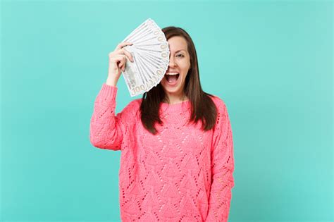 달러 지폐 현금 돈의 많은 무리와 함께 눈을 덮고 유지 입 벌리고 파란색 배경에 고립 된 분홍색 스웨터에 젊은 여자를 흥분 사람들의 라이프 스타일 개념입니다 복사 공간을