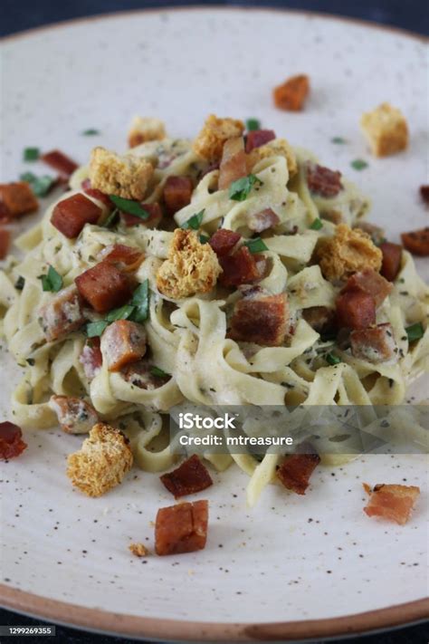 카보나라 소스에 계란 베이컨 프로슈토 햄 판세타 이탈리아 파르메산 치즈와 마늘 화이트 플레이트에 부분 전경에 초점을 맞춘 카르보나라 소스에 집에서 만든 페투치네 파스타의