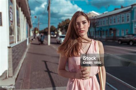 분홍색 드레스 도로 건물 구름의 배경 커피 차 한 잔을 들고 있는 아름다운 소녀 도시에서 여름에 여자 친구와 친구 웅장한 머리 텍스트 무료 공간을 기다리고 있습니다 개념에