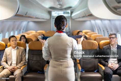 아시아 승무원이 객실 승무원 및 항공사 비즈니스 개념을 위해 비행기에서 이륙하기 전에 안전 벨트를 사용하여 안전 절차를 시연하고 있습니다 알림 메시지에 대한 스톡 사진 및