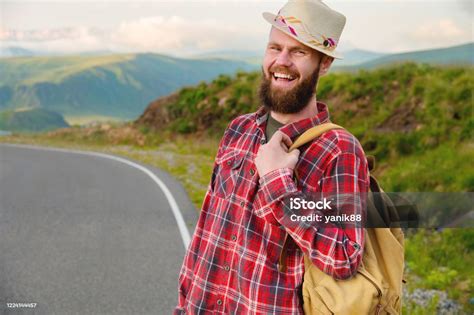 밝은 미소 짓는 수염을 기르는 여행자 의 초상화모자와 하늘과 구름의 녹색 들판을 배경으로 자연에 배낭이 달린 격자 무늬 셔츠 가득 찬에 대한 스톡 사진 및 기타 이미지