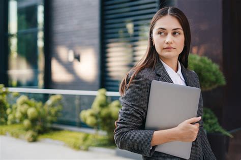 자신감 넘치는 표정을 가진 젊은 백인 사업가가 점심 시간에 사무실 건물 밖에 서있는 손에 노트북을 들고 있습니다 공간을 복사합니다 사무실 밖에서 일하기 위해 노트북 컴퓨터를