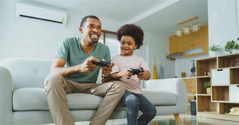 흑인 아프리카계 미국인 아버지와 소파에 앉아 집에서 비디오 게임을 하는 어린 아들 사진 Unsplash의 기쁨 이미지