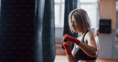 그 소녀는 어떤 사람들을 이길 수 있습니다 여성 권투 선수가 가방을 펀치하고 있습니다 금발은 체육관에서 운동을합니다 사진