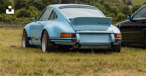 하얀 구름 낀 하늘 아래 푸른 잔디 위에 주차된 파란색과 검은색 자동차 사진 Unsplash의 무료 자동차 이미지