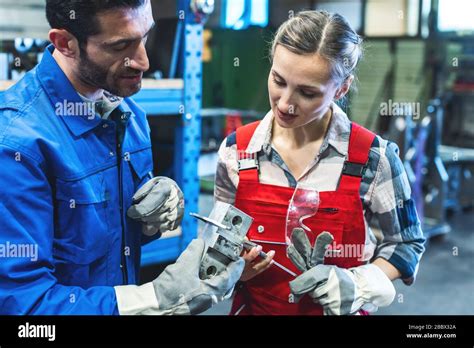 Woman And Man Worker Checking Measurements Of Metal Work Piece Stock
