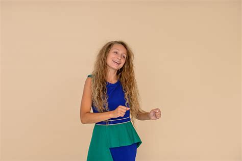 긴 금발 곱슬 머리를 가진 소녀는 스튜디오에서 베이지 색 배경에 미소와 춤을 반 길이의 초상화 25 29세에 대한 스톡 사진 및 기타 이미지 Istock