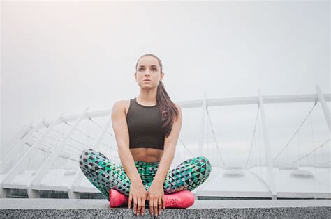 잘 Buil과 자신감 젊은 여자 로터스 위치에 앉아서 손으로 다리를 잡고 그녀는 곧장 앞으로 보인다 모델은 조용 하 고 조용