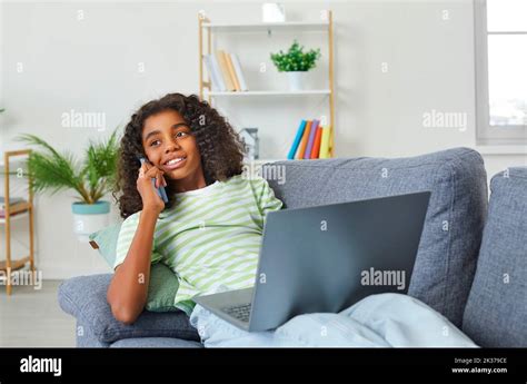 Dark Skinned Teenage Girl Is Having Fun Talking On Phone And Using Laptop At Same Time Stock