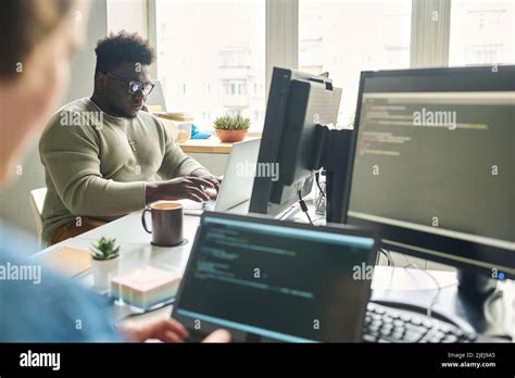 Programmers Working At Office Desk With Laptops Writing Codes For New