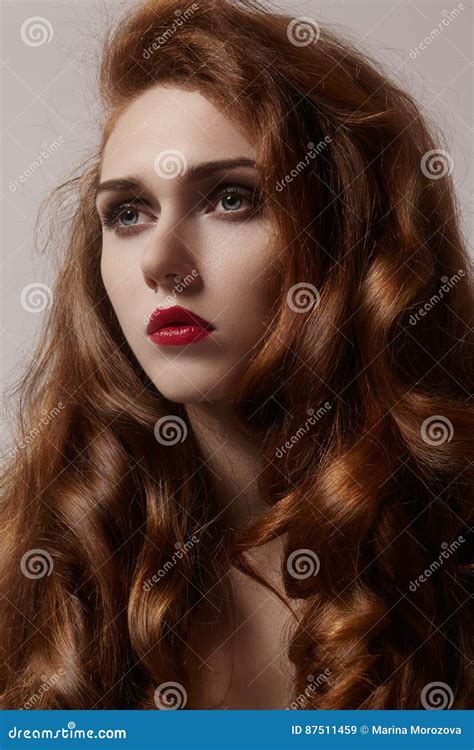 A Beautiful Ginger Fluffy Cat Sits Among The Grass And Thickets Of