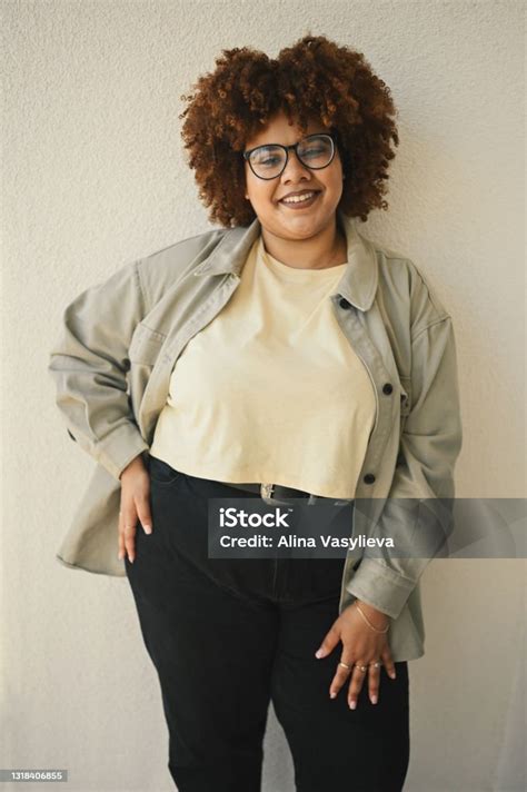 아름다운 행복한 미소 매력적인 플러스 크기 아프리카 흑인 여성 아프로 머리 포즈 베이지 색 티셔츠 청바지 베이지 색 배경에