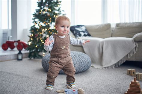 바닥에 서 있는 귀여운 1 년 된 아기의 초상화 첫 번째 단계 개념입니다 크리스마스 장식 배경 12 17 개월에 대한 스톡 사진