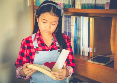 Premium Photo Girl Reading Book By Bookshelf