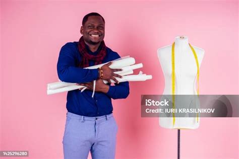 아프리카 계 미국인 남자 재단사 재봉사 워크샵 세련된 남성 모델 의류 디자이너가 스튜디오 손의 분홍색 배경에 마네킹 옆에 포즈를 취하여 공간 카피 스페이스를 디자인합니다