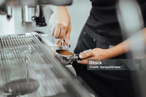 탬퍼를 사용하여 분쇄 커피를 포터필터에 밀어 넣는 바리스타 바리스타가 커피 머신으로 커피를 만드는 모습을 가까이서 볼 수 있습니다 커피 소유자 개념입니다 바리스타에 대한