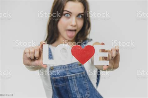 젊은 아름 다운 소녀는 회색 배경에 있습니다 데님 수트와 화이트 티셔츠를 입고 사랑의 말씀으로 표지판을 들고 있다 T 셔츠에