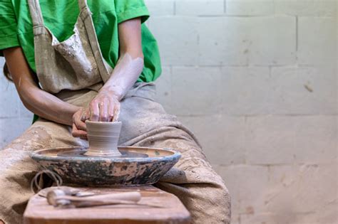 그녀의 작업복에 Concentrsted 여자의 자른된 사진 그녀 손에 의해 원형 바퀴에 텍스트 만들기 도자기 제품을 위한 복사 공간 흰색 벽돌 벽 배경 작업 영역 안에 앉아