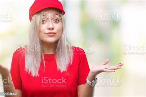 젊은 금발 여자 격리 된 배경 우 둔 하 고 혼란 스 러 워 식으로 발생 하는 손과 팔에 빨간 모자를 쓰고 의심 개념입니다 감정에 대한 스톡 사진 및 기타 이미지 Istock