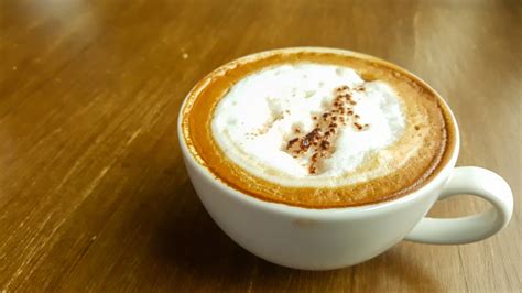 뜨거운 카푸치노 크림 우유 거품이 나무 테이블 신선도 아침 또는 점심 식사 후에 커피 한 잔의 최고 볼 수 있습니다 그것은 노동자 또는 책임자에 대 한 좋아하는 음료입니다