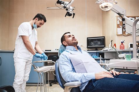 신뢰할 수 있는 치과 치료 젊은 치과 의사는 환자의 치아를 검사하기위한 장비를 준비하고 있습니다 수평 샷 2명에 대한 스톡 사진 및 기타 이미지 Istock