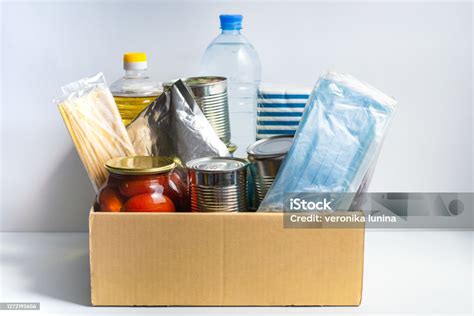 자선 기부를 위한 음식이 있는 상자 통조림 식품 파스타 절인 오이 식물성 기름 차 종이 냅킨 보호 마스크 음식 배달 또는 음식 기부 개념 저장고 일터에 대한 스톡 사진 및