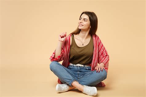 캐주얼 옷에 아름 다운 웃는 젊은 여자의 초상화 스튜디오에서 파스텔 베이 지 벽 배경에 고립 된 옆을 보고 앉아 사람들은 진심으로 감정 라이프 스타일 개념입니다 복사 공간을