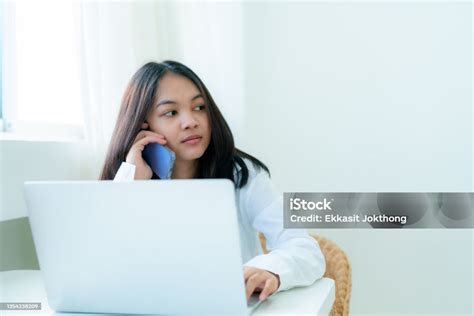 세로 귀여운 아시아 십대 긴 머리를 입고 긴 머리 에 전화와 함께 이야기 하 고 책상에 노트북 컴퓨터와 함께 온라인 공부 행복 하 게 20 24세에 대한 스톡 사진 및 기타