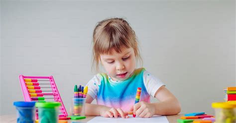 테이블에 앉아 화려한 왁스 크레용으로 그림을 그리는 아름다운 소녀 가정이나 유치원에서 아이들을위한 학습 교육 활동 사진