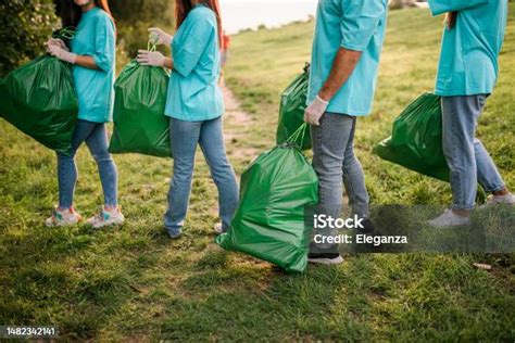 도시 잔디밭에서 쓰레기를 치우는 야외 청소부의 클로즈업 여자와 남자가 비닐 봉지를 들고 걸어가는 뒷모습 야외 쓰레기 수거 개념 Charitable Foundation에 대한