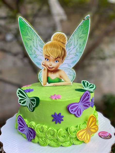 A Green Cake With A Tinkerbell Figure Sitting On Its Top And