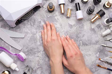 네일 케어 콘크리트 질감에 분홍색 부드러운 매니큐어에 의해 그려진 손톱을 만드는 아름다운 여성 손 전문 매니큐어 도구 세트 옆에 여성의 손 뷰티 케어 네일아트에 대한 스톡